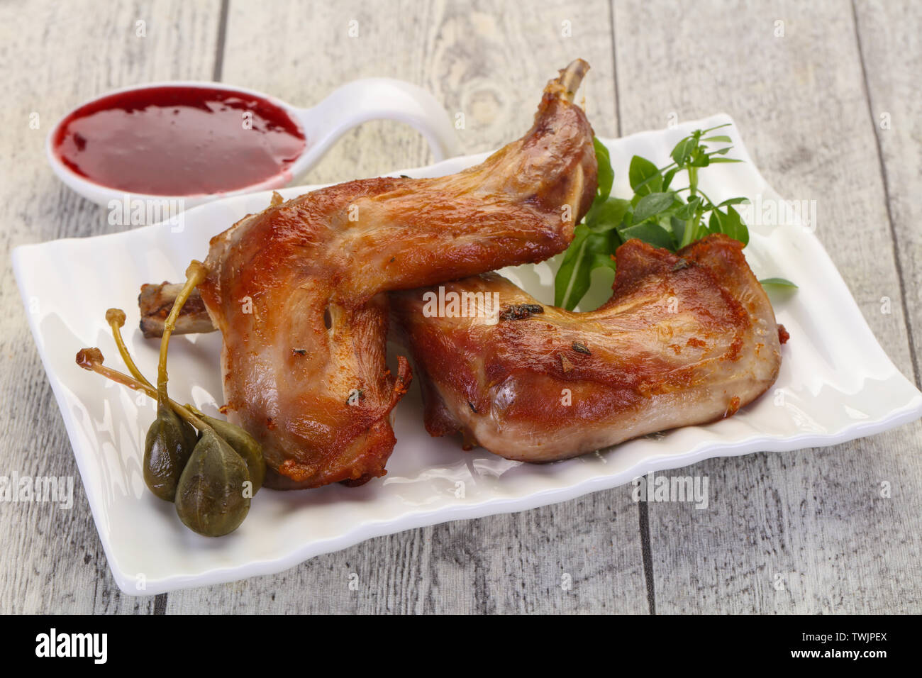 Roasted rabbit legs with cowberry sauce Stock Photo - Alamy