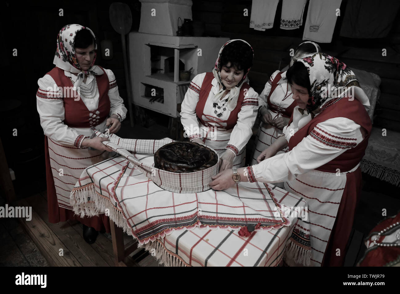 Belarusian women in traditional garment preparing rye bread during a re ...
