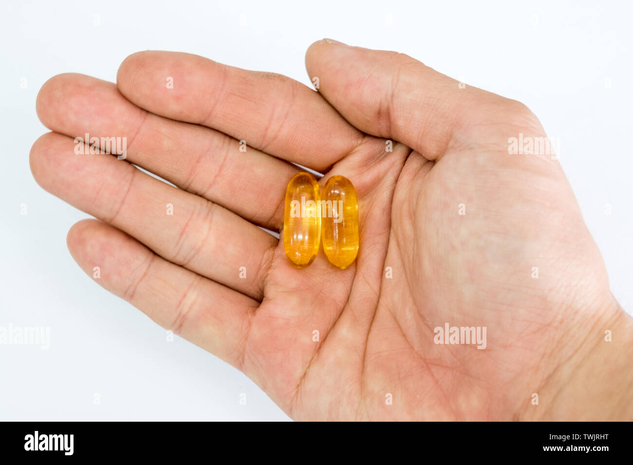 Hand palm holding omega fatty acids fish oil pills Stock Photo - Alamy