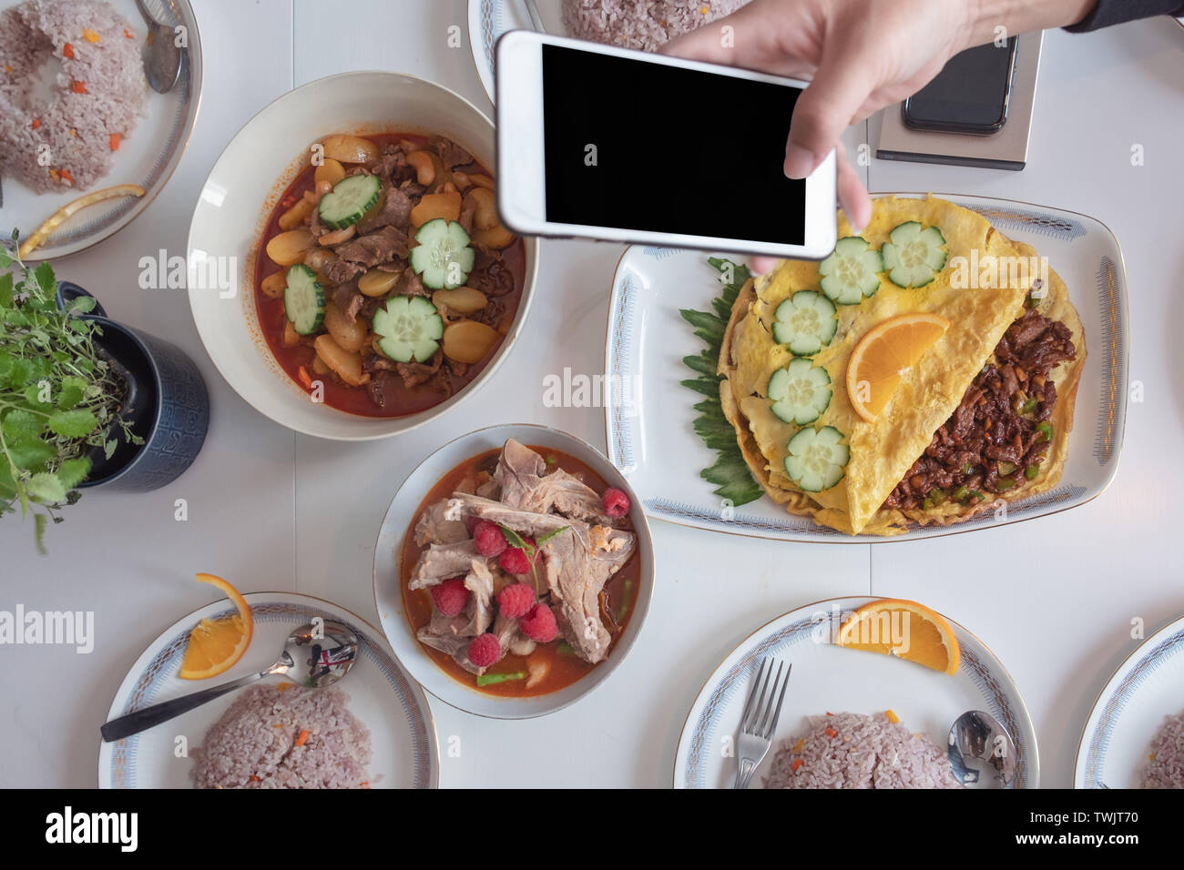 Variety of food with hand using smartphone take a photo on dining table ...