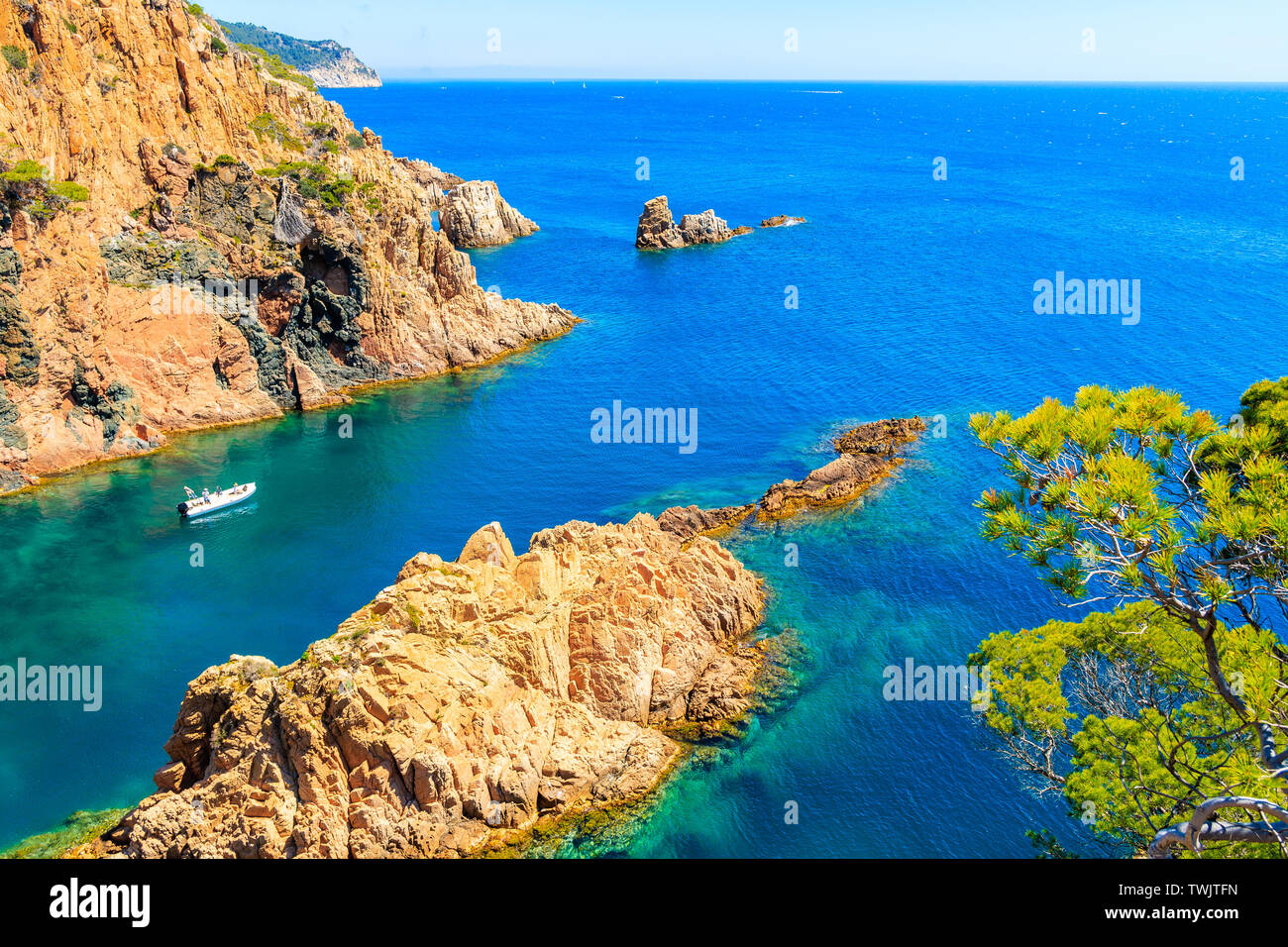 White boat in beautiful sea cove of Cala Marquesa with green pine trees ...