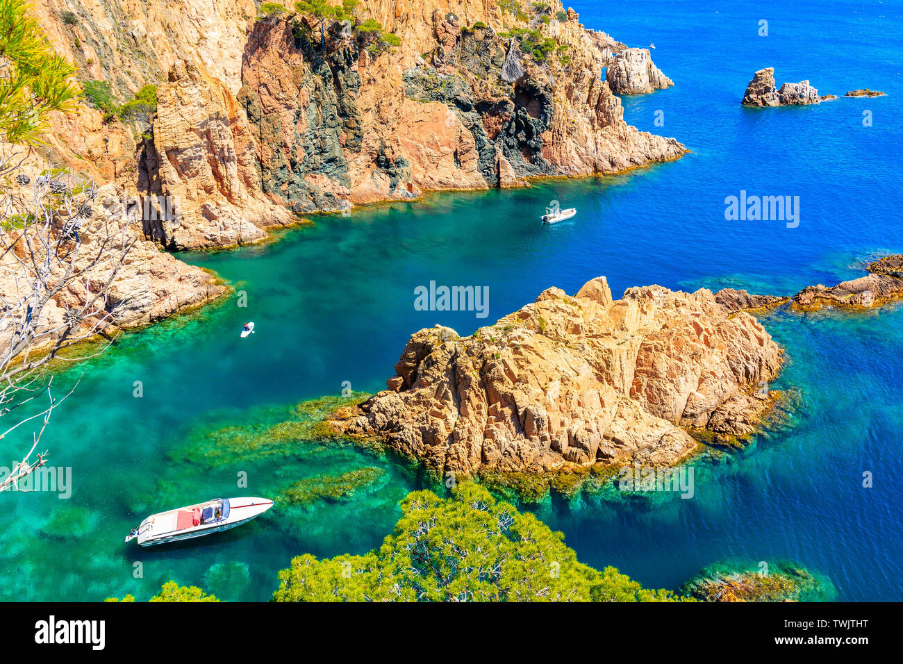 Biats in beautiful sea cove of Cala Marquesa with green pine trees on ...
