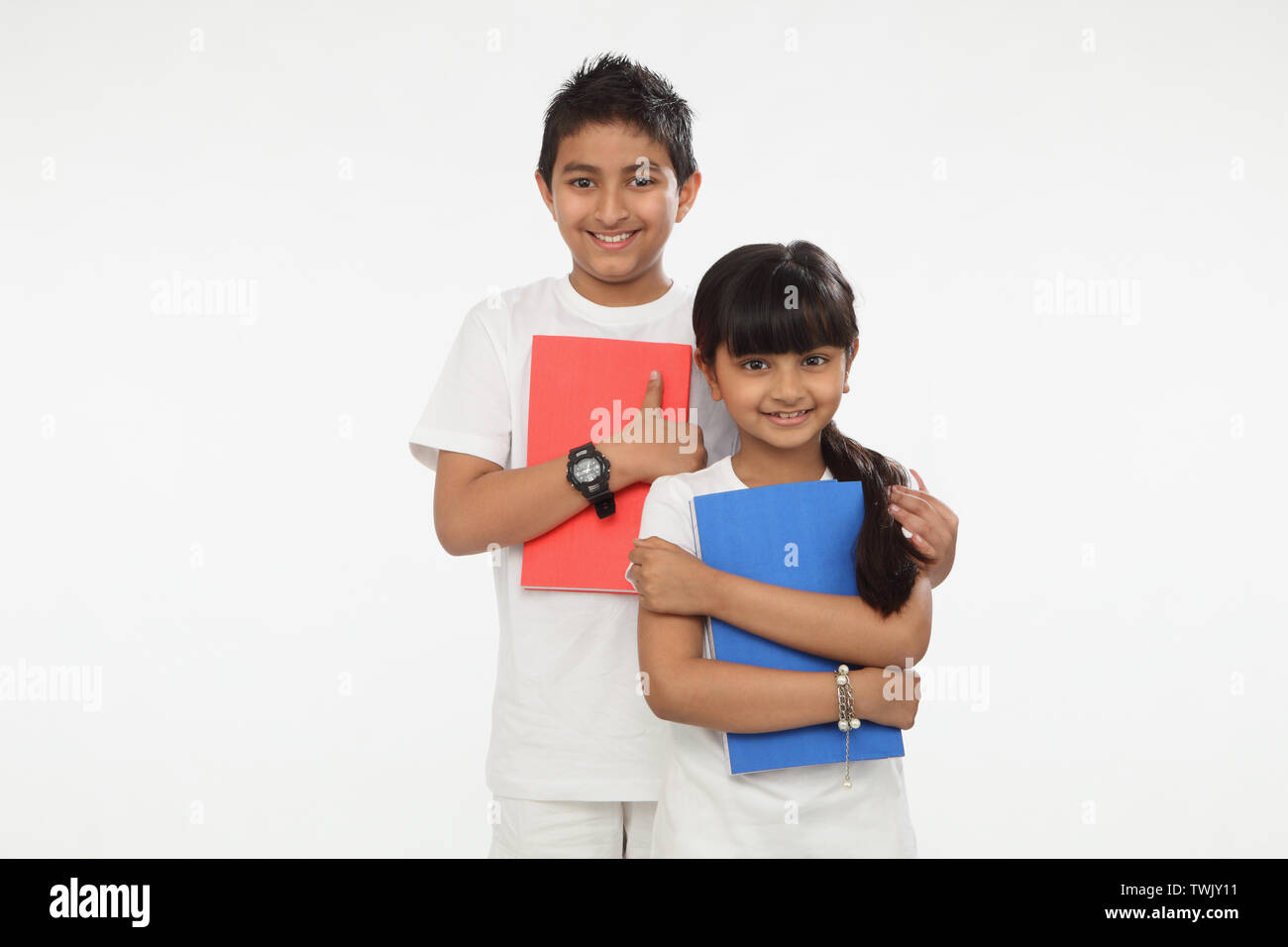Portrait of two students holding books and smiling Stock Photo - Alamy