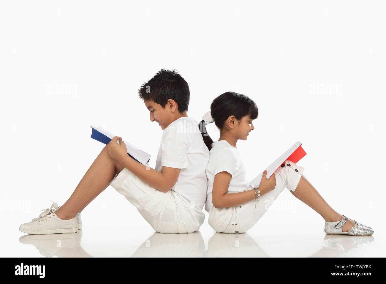 Two students sitting back to back and reading books Stock Photo - Alamy