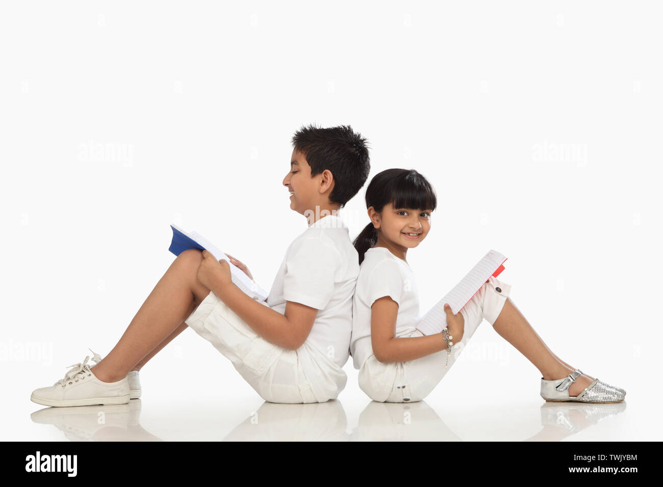 Two students sitting back to back and reading books Stock Photo - Alamy