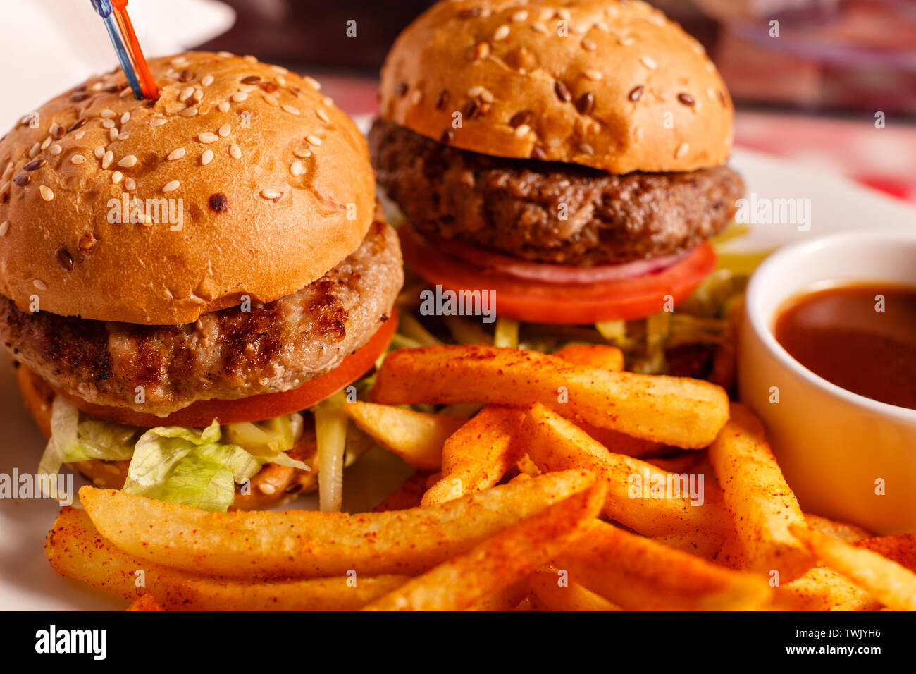 Two mini burgers in the restaurant. Sesame bun, meat Patty, tomato ...