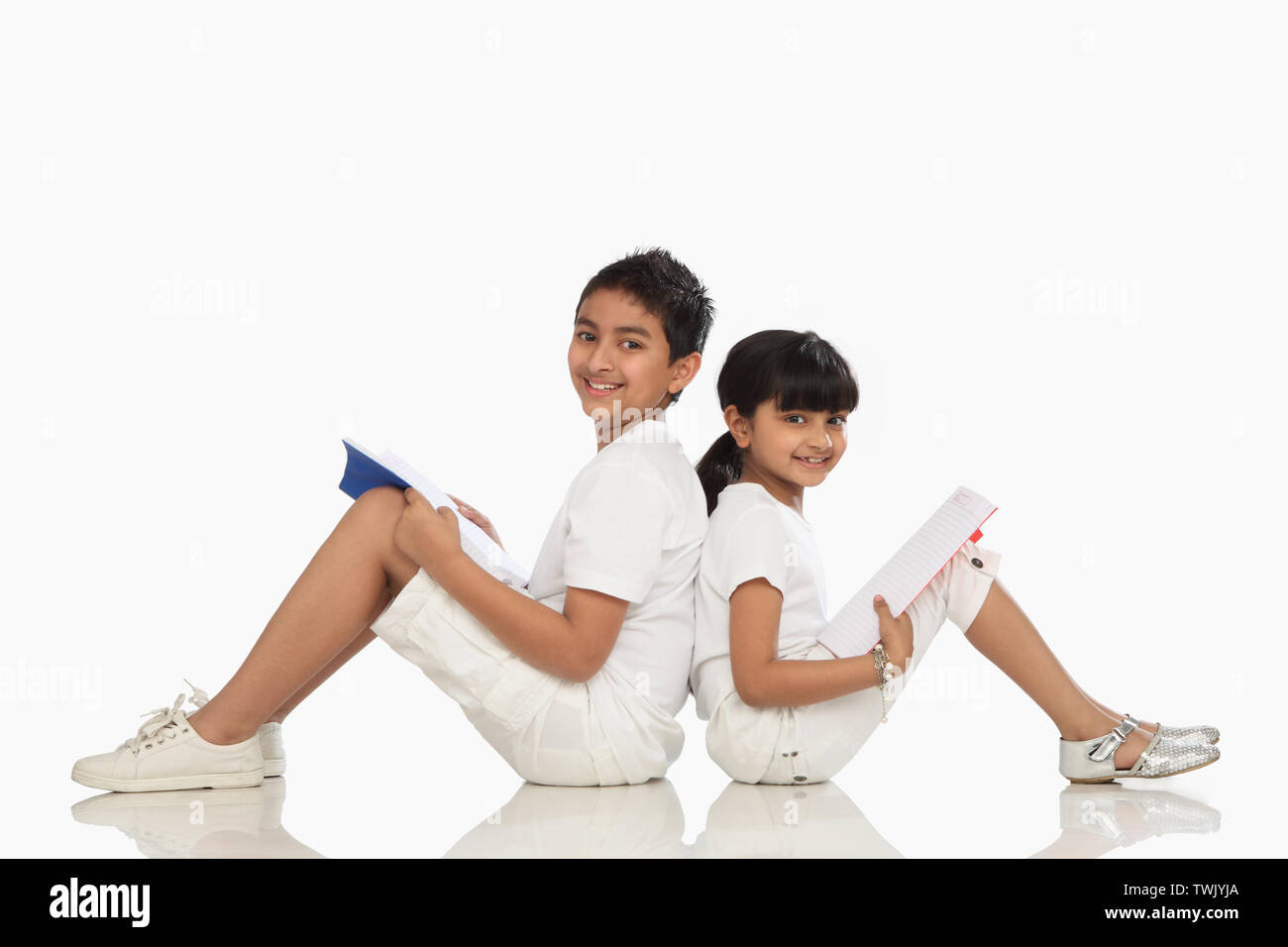 Two students sitting back to back and reading books Stock Photo - Alamy
