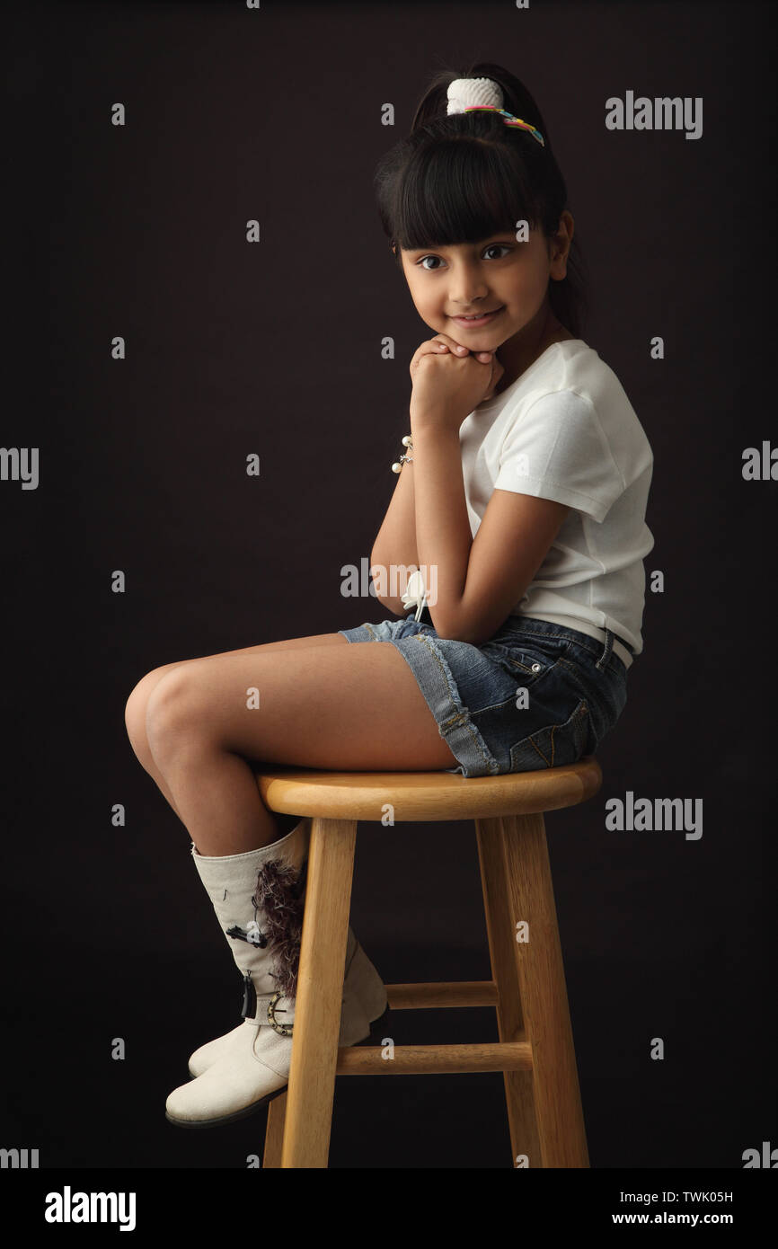 Girl sitting on a stool and smiling Stock Photo - Alamy