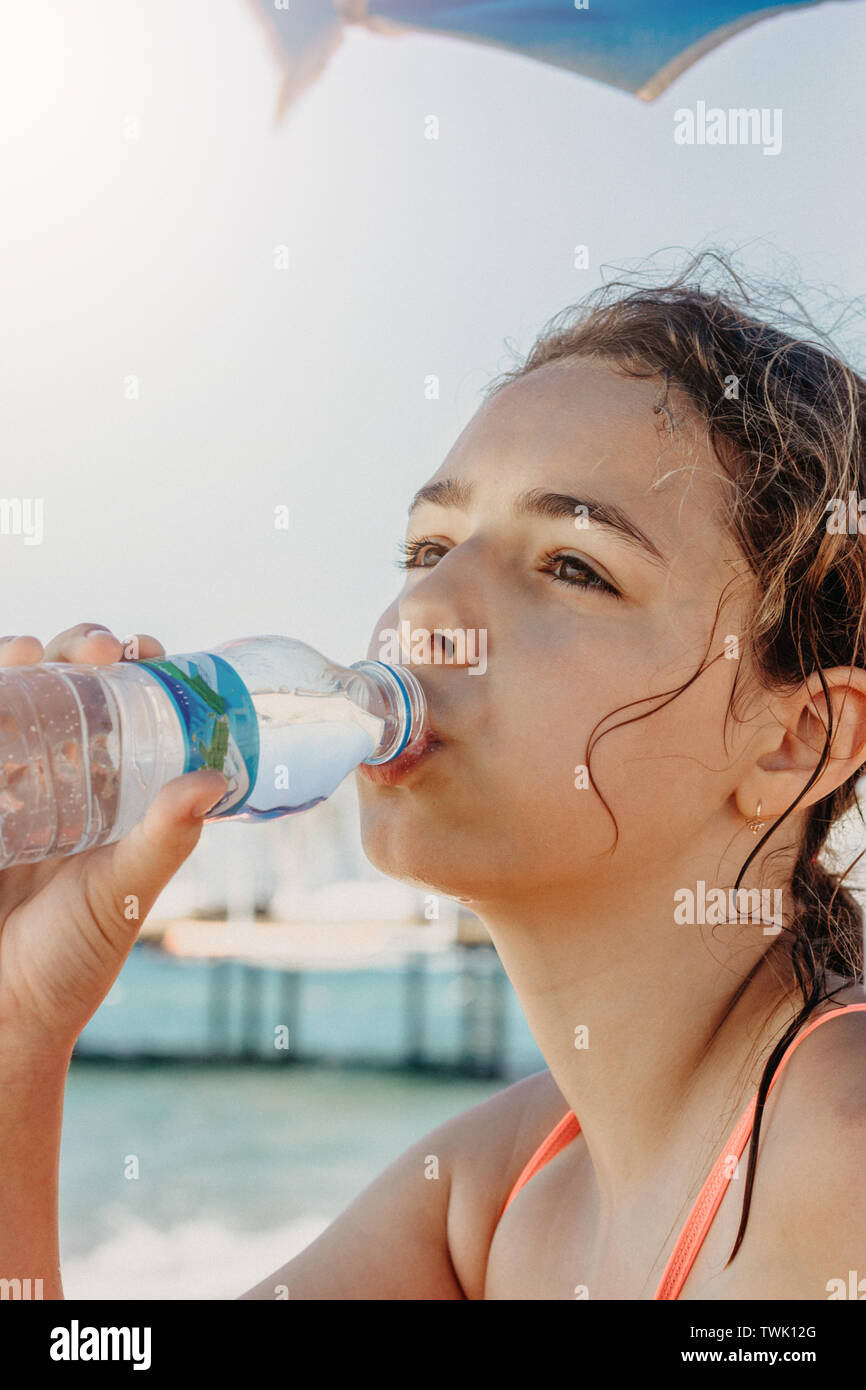 Sporty woman drinking water at the sea at sunset hi-res stock ...
