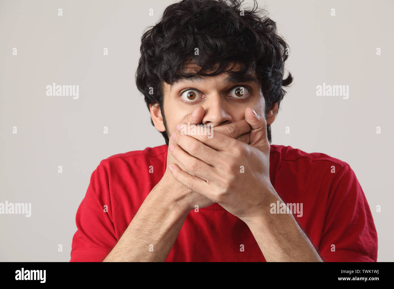 Man covering mouth with hands Stock Photo - Alamy