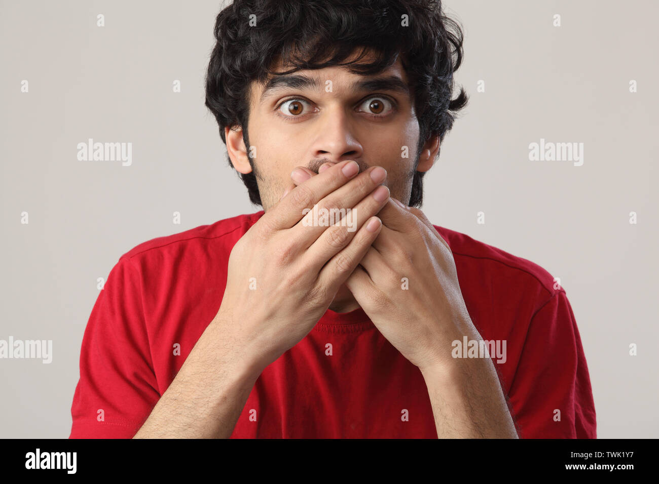 Man covering mouth with hands Stock Photo - Alamy
