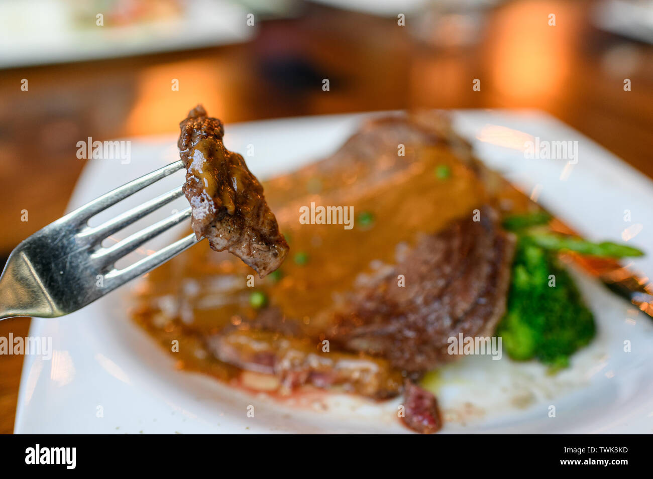 Fork dipping grilled rib eye beefsteak sliced with medium rare Stock ...