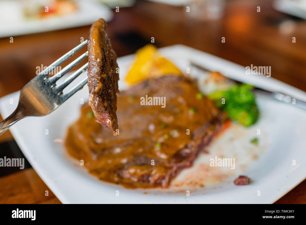 Fork dipping grilled rib eye beefsteak sliced with medium rare Stock ...