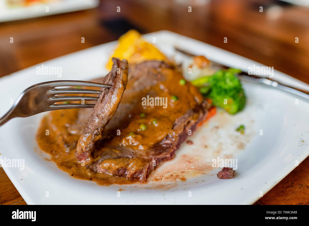 Fork dipping grilled rib eye beefsteak sliced with medium rare Stock ...
