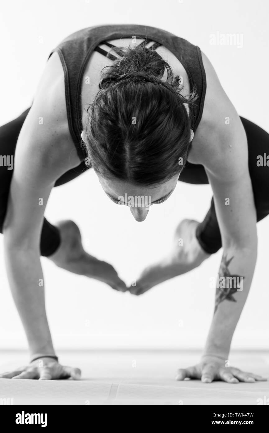 A brunette woman in her 30’s practicing yoga at home, concentrated on a ...