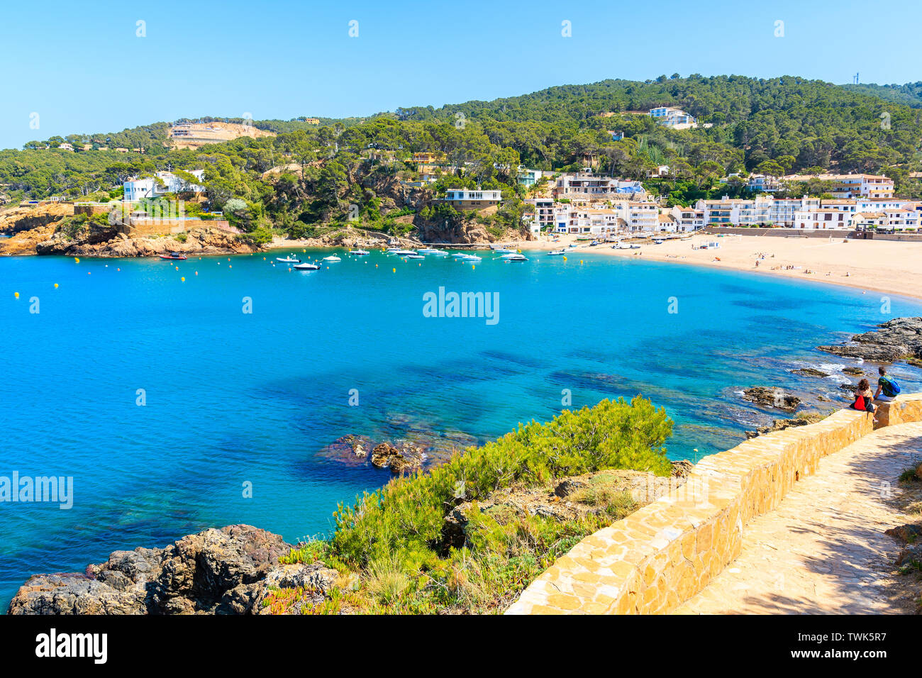 Couple of tourists sitting on coastal path and looking at beautiful bay ...