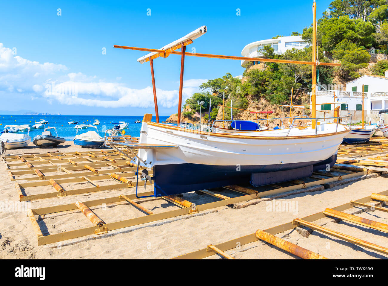Traditional fishing boat on Sa Riera beach with sea and village houses ...