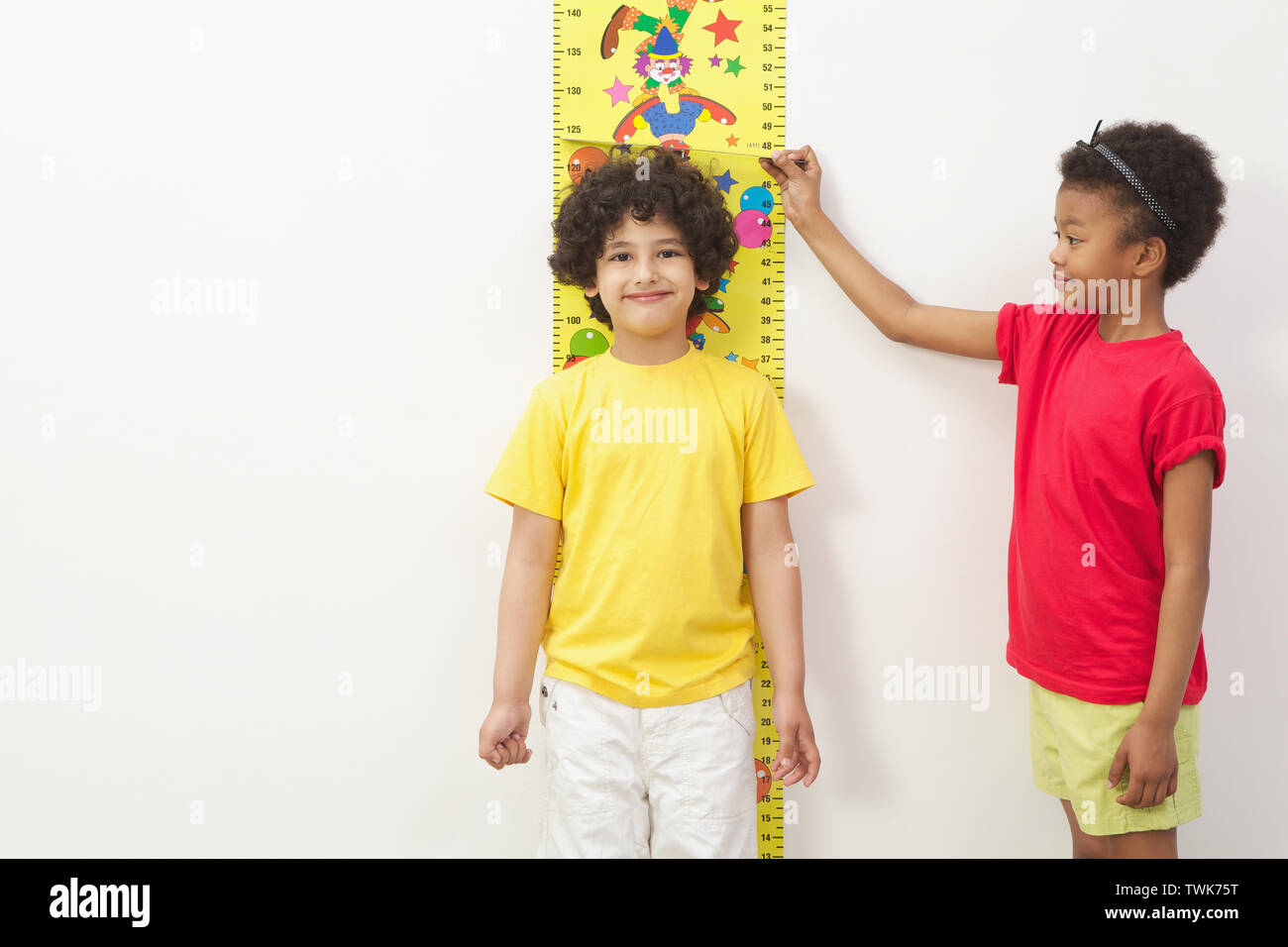 Girl measuring her friend height Stock Photo - Alamy