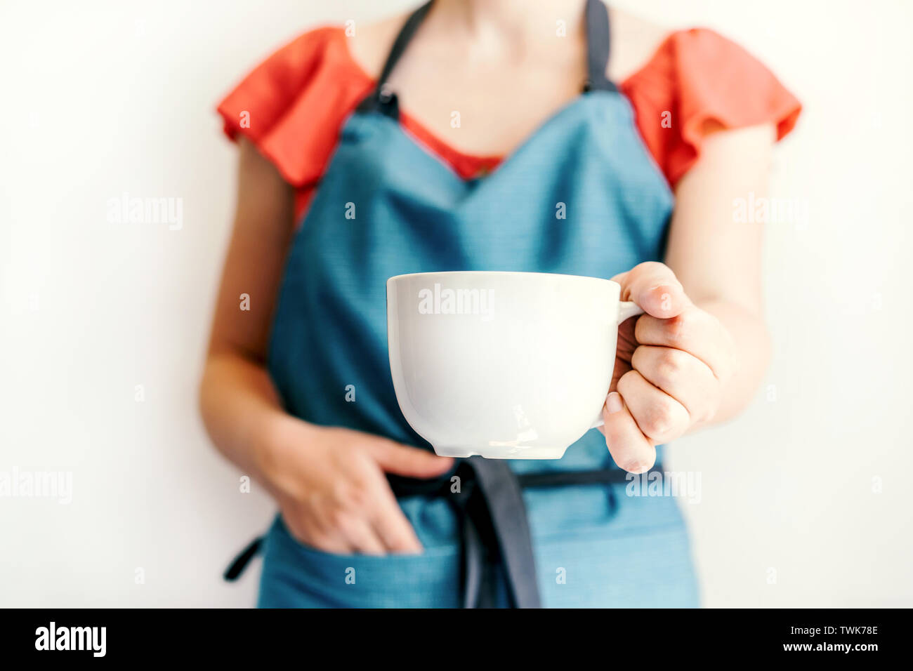 Female hand holds and stretches a large white mug, suitable as a mockup ...