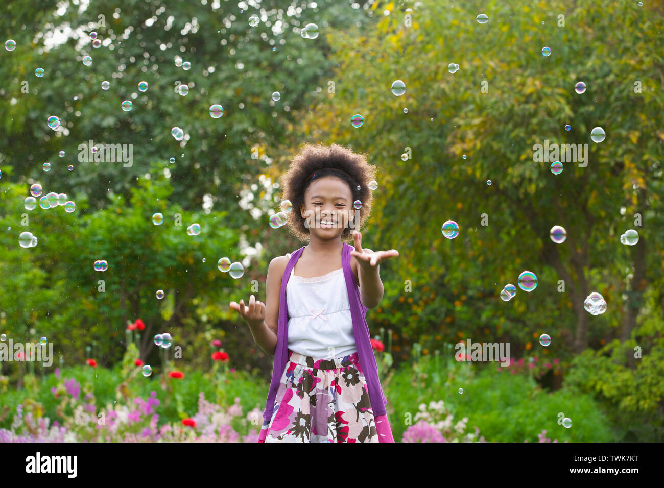 Girl trying to hold floating bubbles Stock Photo - Alamy