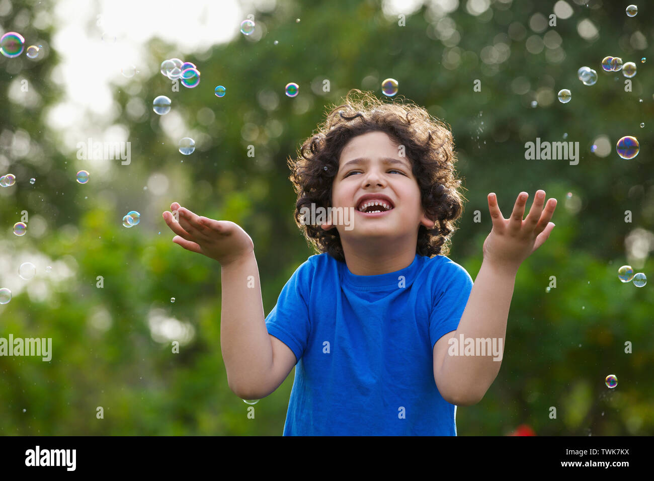 Boy trying to hold floating bubbles Stock Photo - Alamy