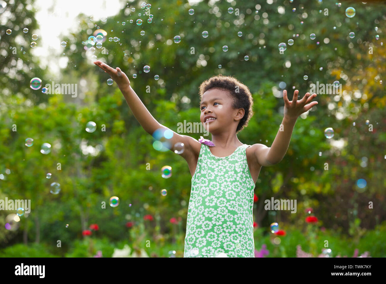 Girl trying to hold floating bubbles Stock Photo - Alamy
