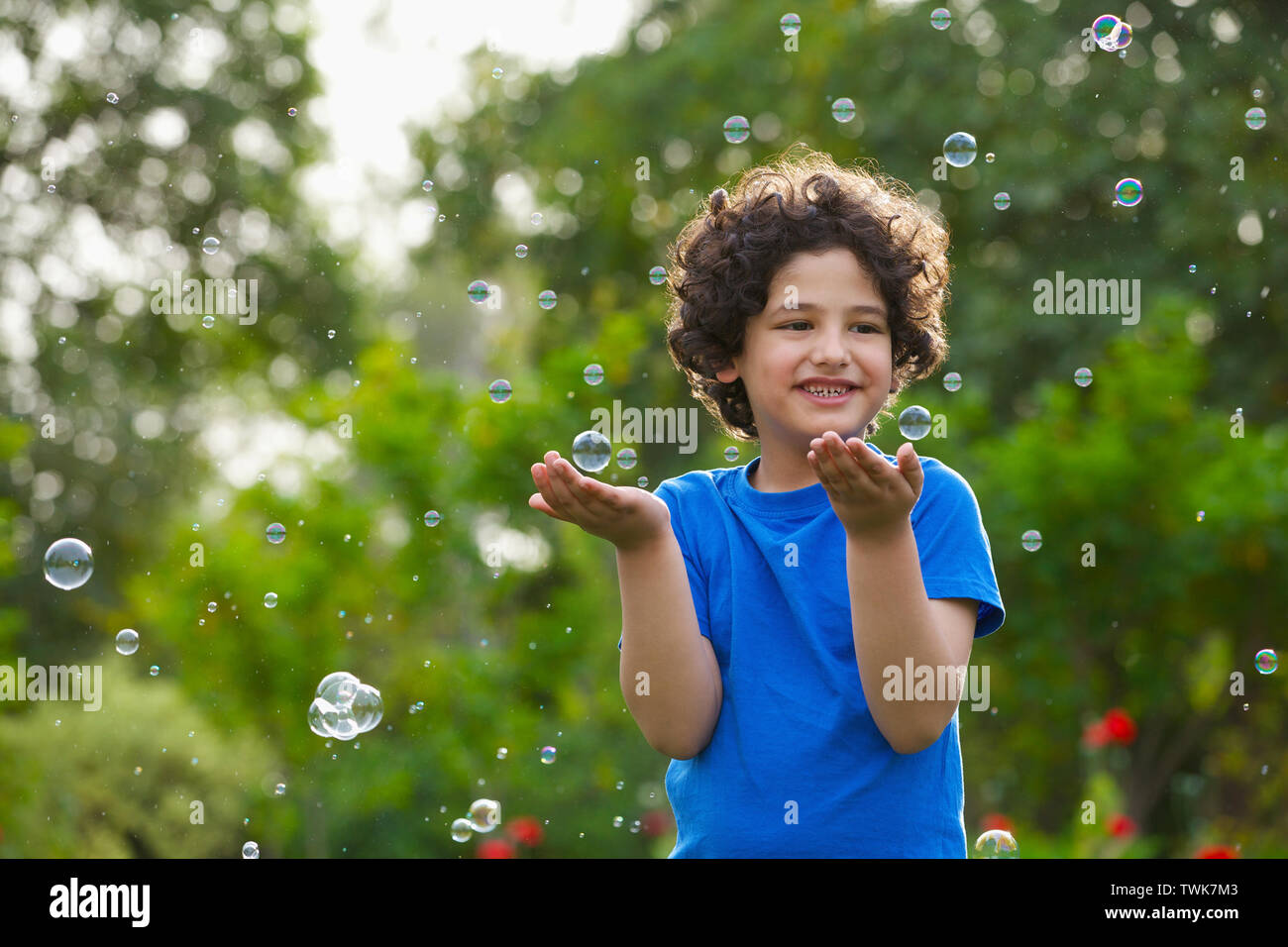 Boy trying to hold floating bubbles Stock Photo - Alamy
