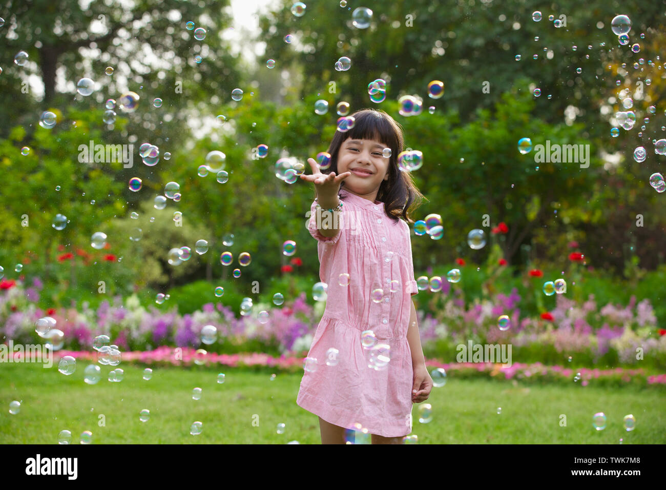 Girl trying to hold floating bubbles Stock Photo - Alamy