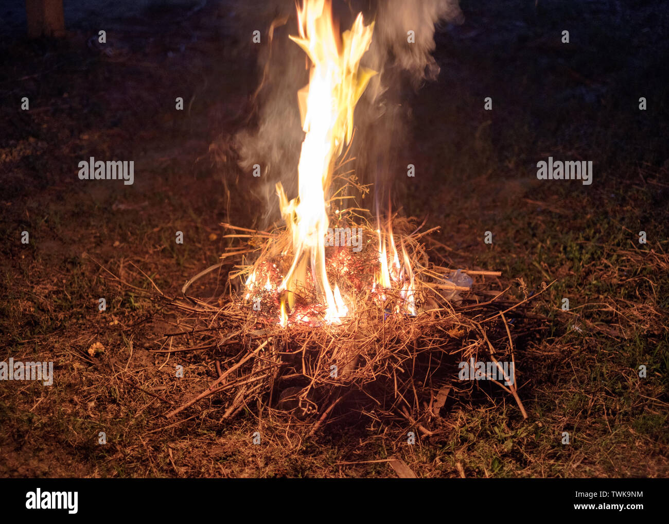 Camping fire on ground with dry straw as fuel Stock Photo - Alamy