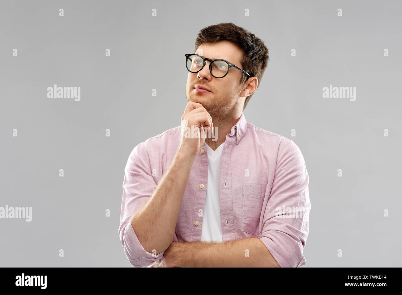 thinking young man in glasses over grey background Stock Photo - Alamy