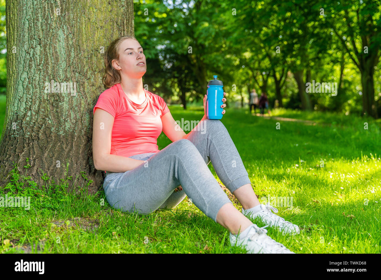 A young woman takes a break from sport and sits under a tree Stock ...