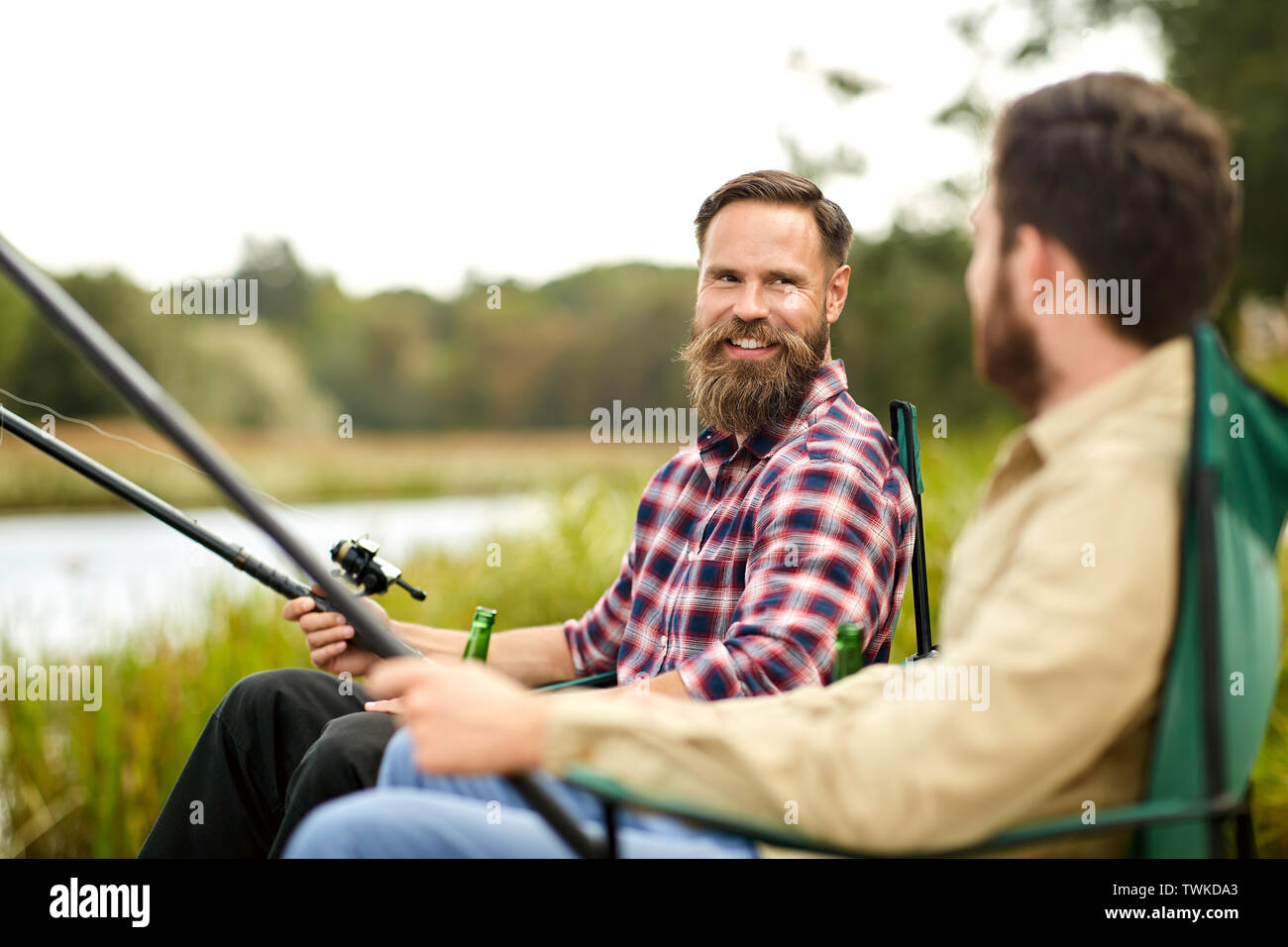 happy friends with fishing rods on lake Stock Photo - Alamy