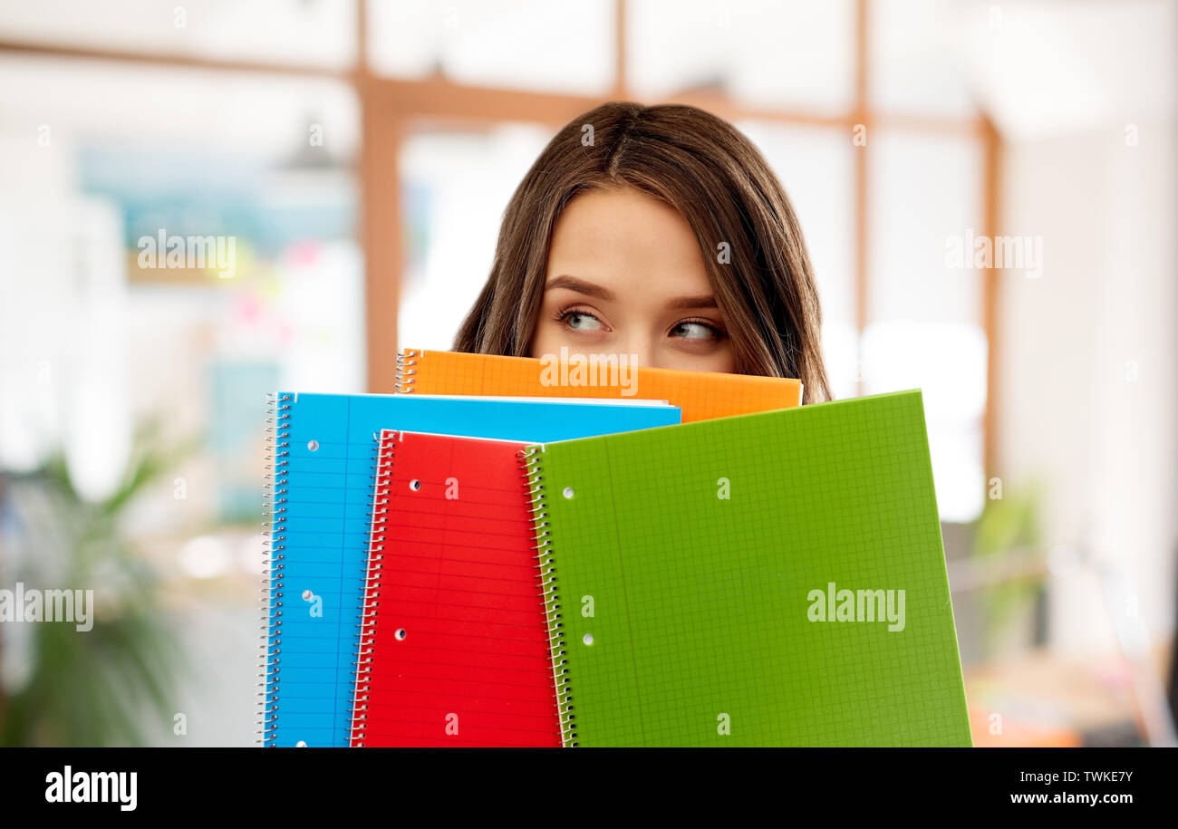 teenage student girl hiding behind notebooks Stock Photo - Alamy