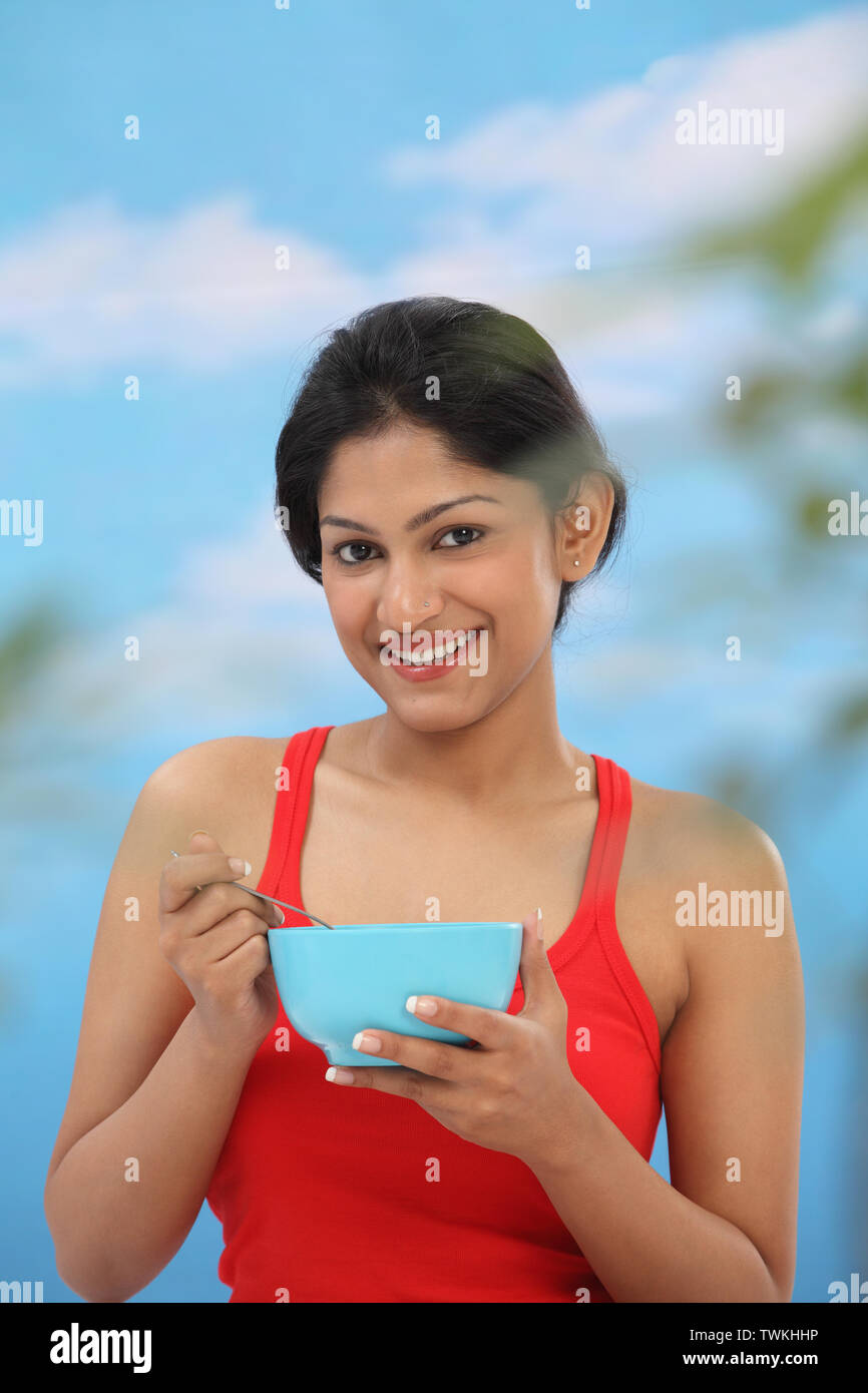 Portrait of a woman eating from a bowl Stock Photo - Alamy