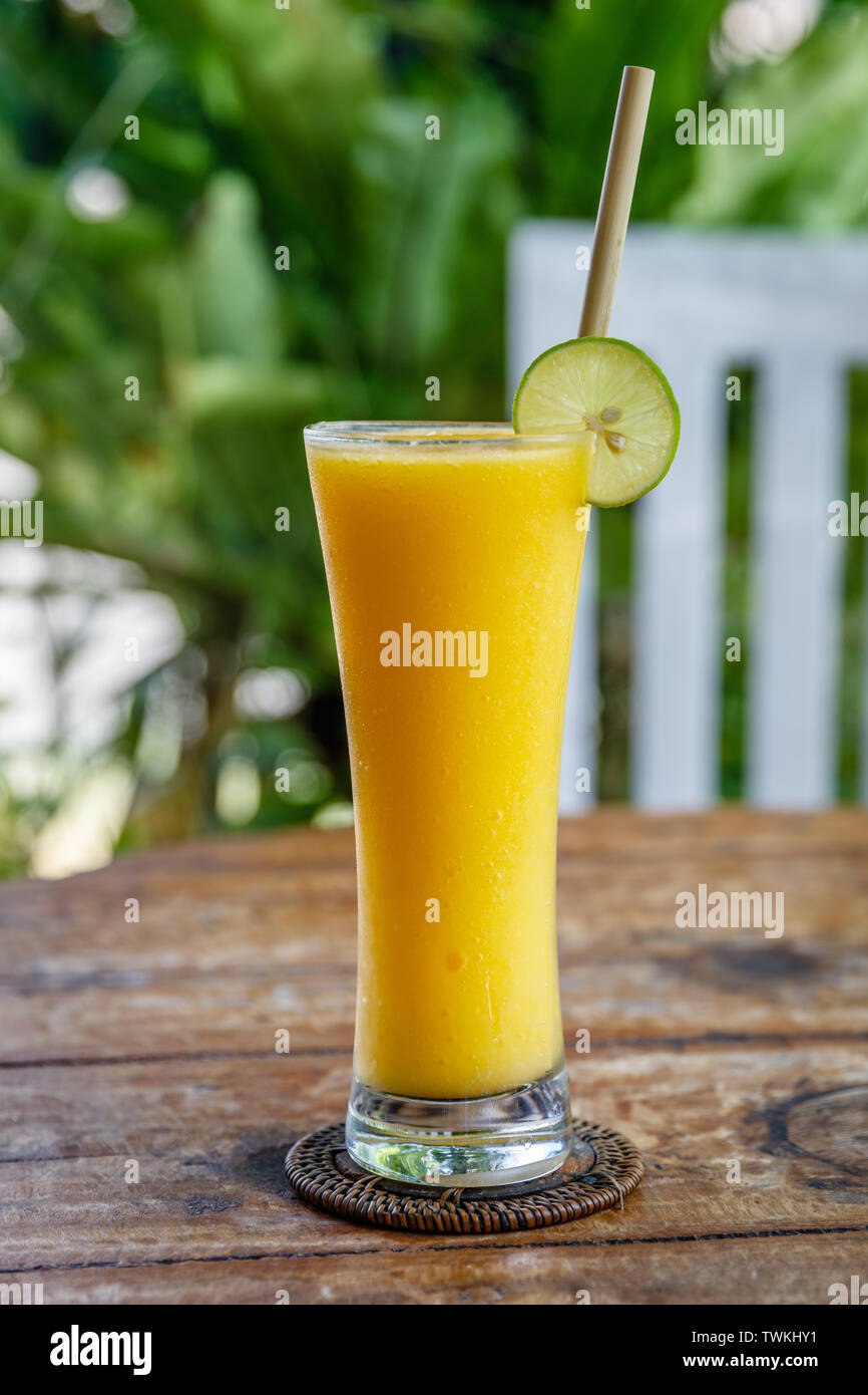 Mango juice in a tall glass with bamboo straw, decorated with lime ...