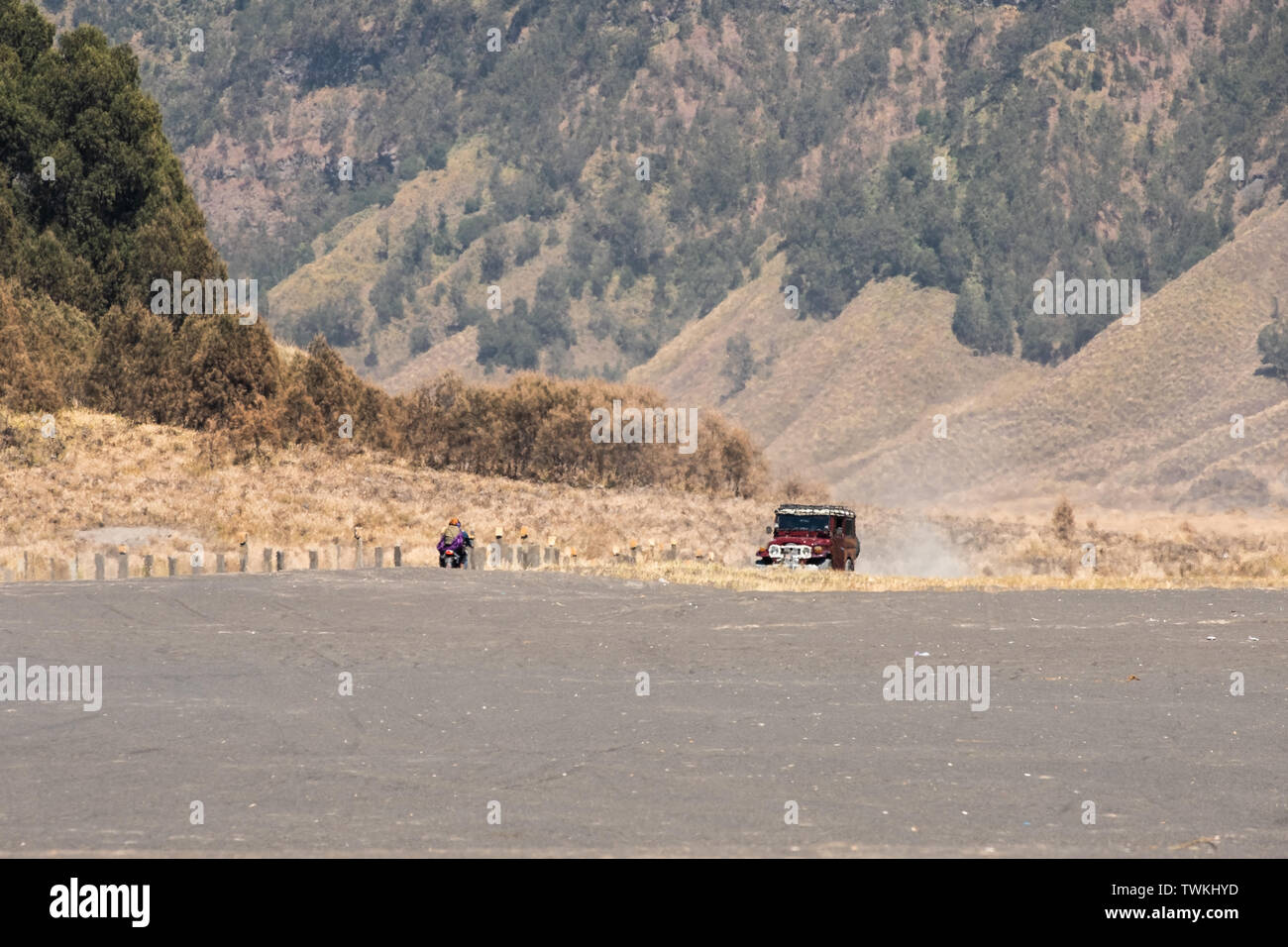 Scorching desert with four wheel car and bicycle on volcano foothill ...