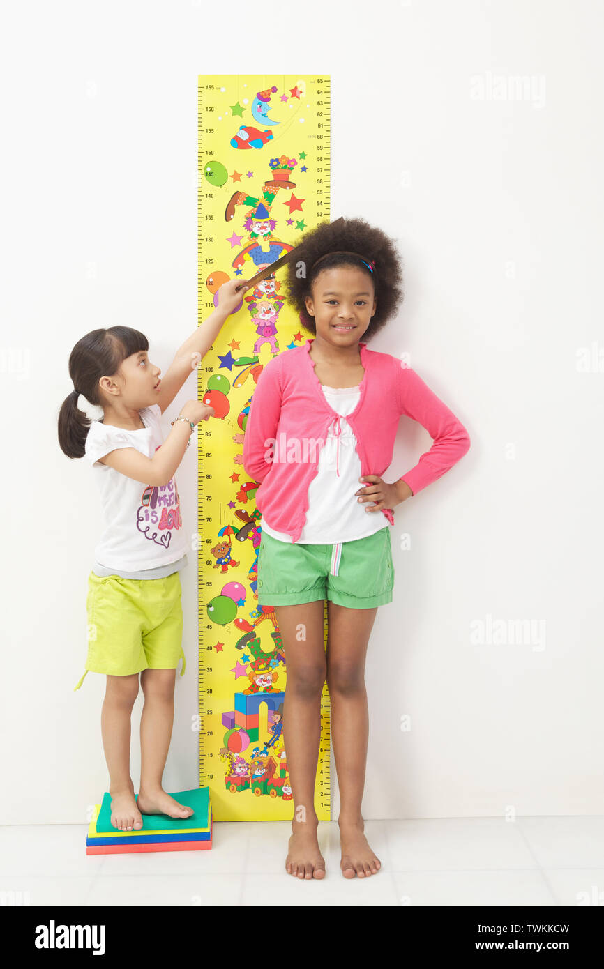 Little girl measuring height of her friend Stock Photo - Alamy Little girl measuring height of her friend Stock Photo - Alamy