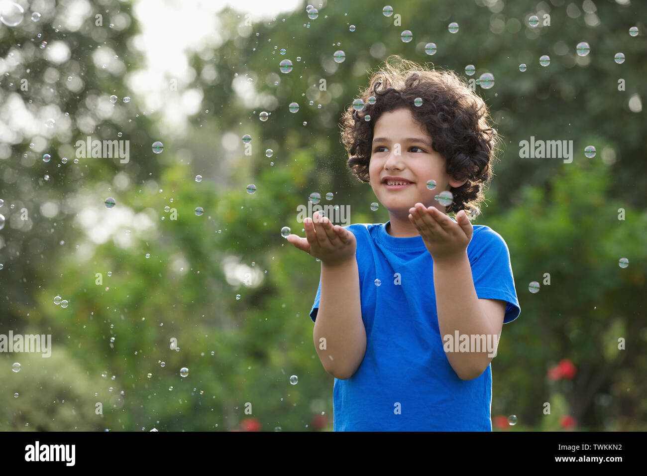 Boy trying to hold floating bubbles Stock Photo - Alamy