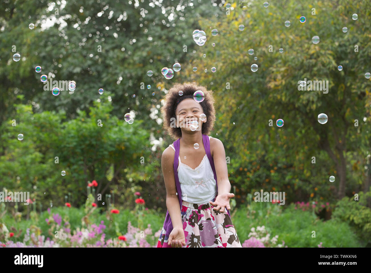 Girl trying to hold floating bubbles Stock Photo - Alamy