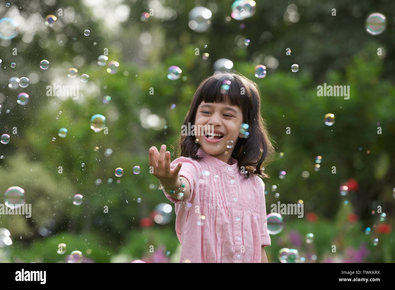 Girl trying to hold floating bubbles Stock Photo - Alamy