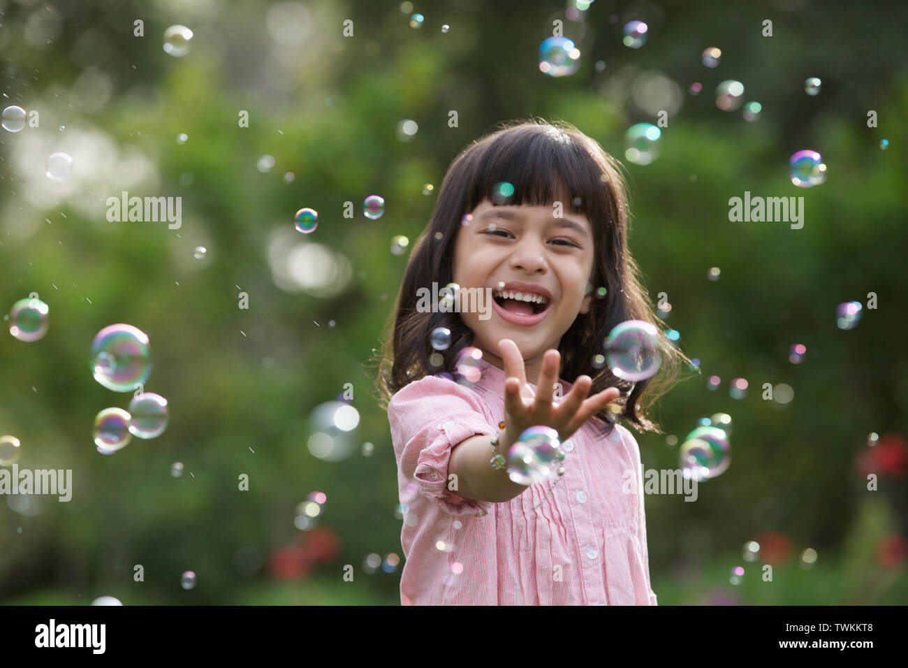 Girl trying to hold floating bubbles Stock Photo - Alamy