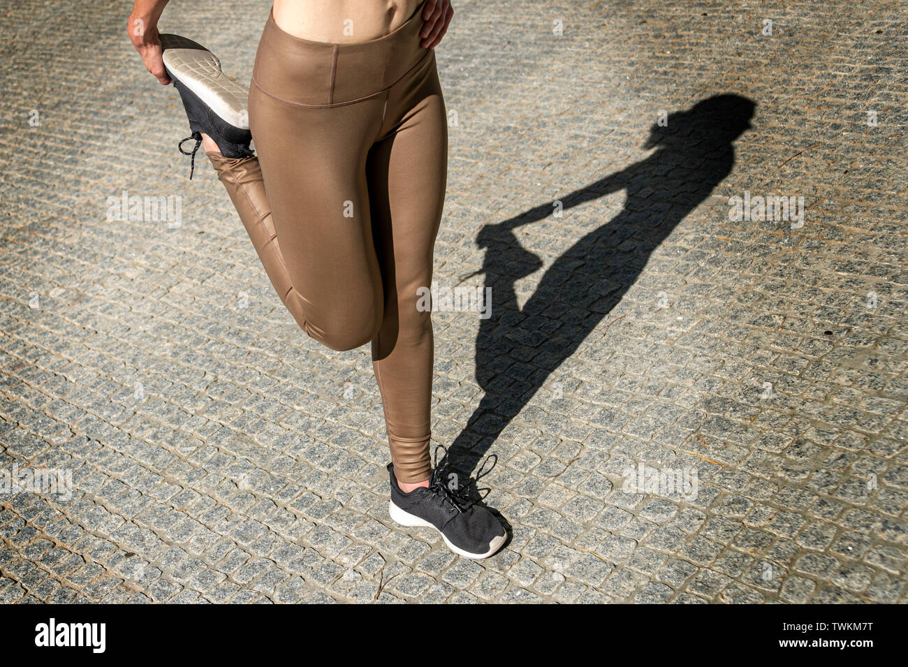 sporty woman doing a leg stretch warm up exercise, shadow of person ...