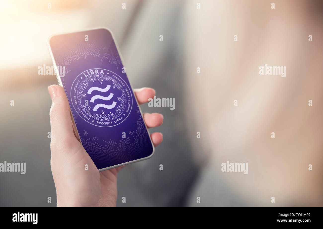 Hand holding smartphone with Libra symbol on screen. New era in e ...