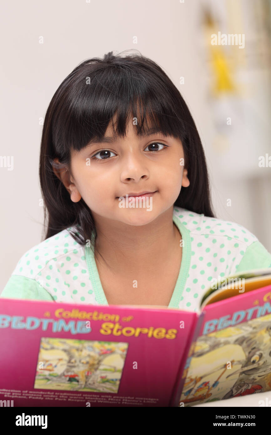 Girl reading a storybook Stock Photo - Alamy