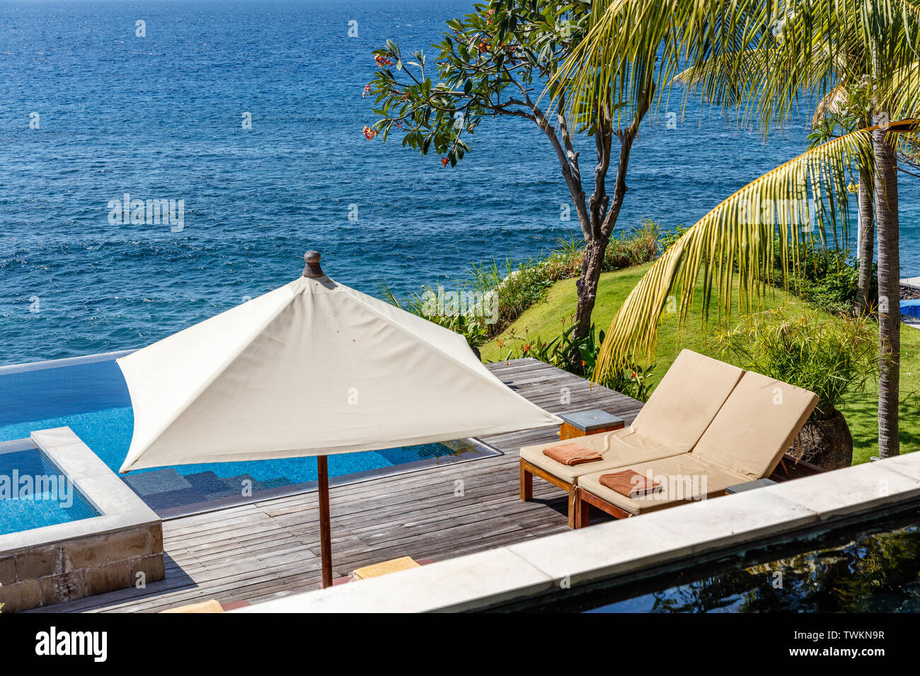 Sun lounges with sun umbrellas near a swimming pool with ocean view ...