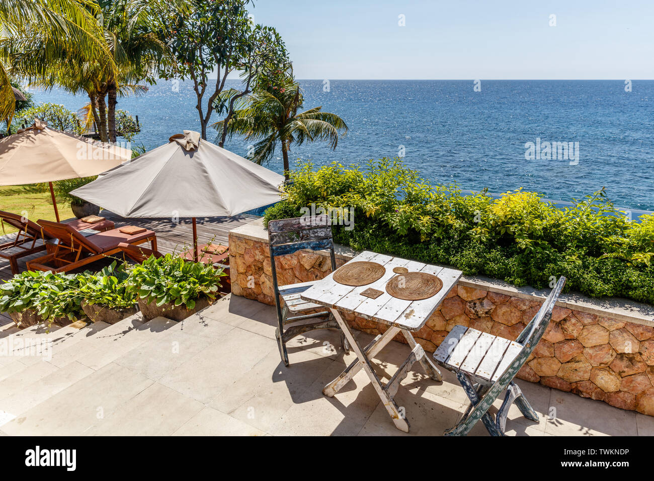 Wooden table and chairs at a outdoor cliff cafe with ocean view, Amed ...