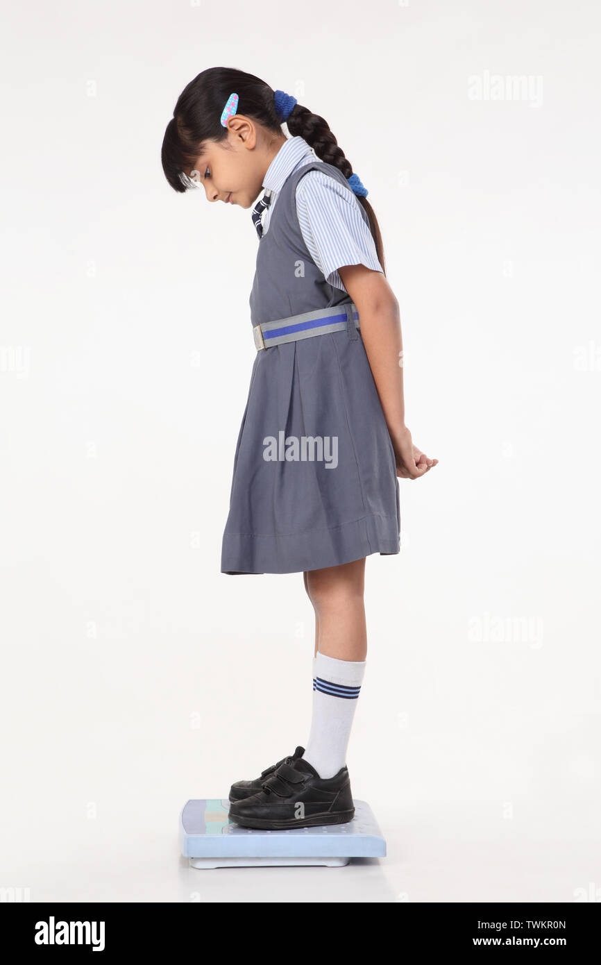 Girl weighing herself on a weight scale Stock Photo - Alamy