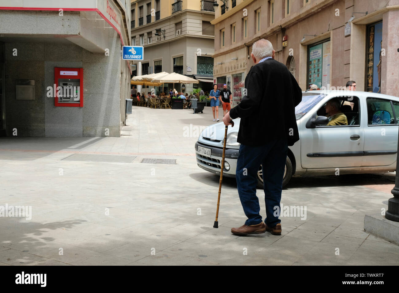 Old gray haired man with a cane stopping to let a car before crossing ...