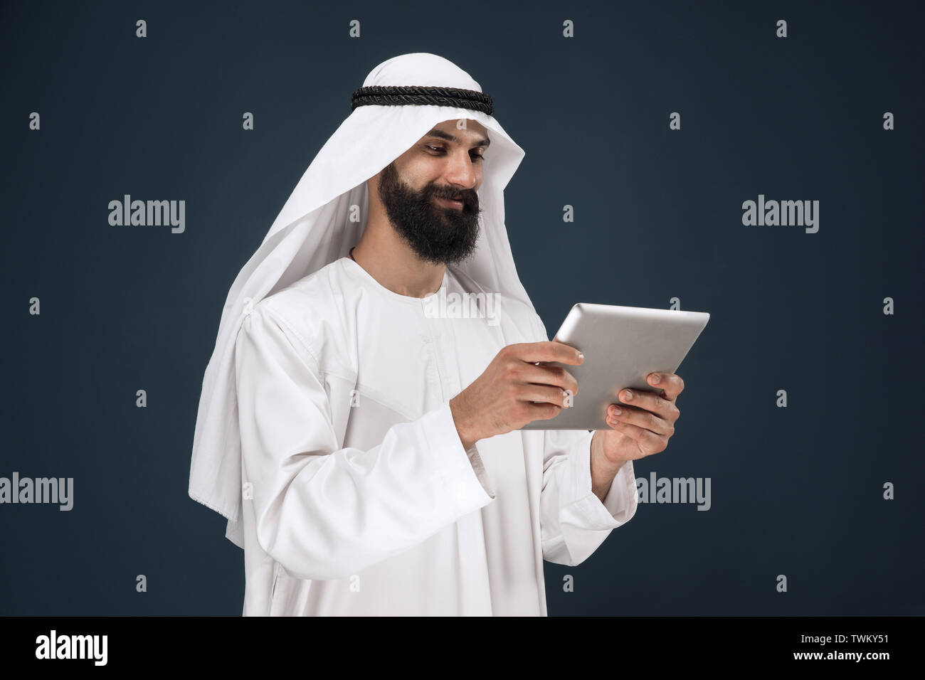 Half-length portrait of arabian saudi businessman on dark blue studio ...