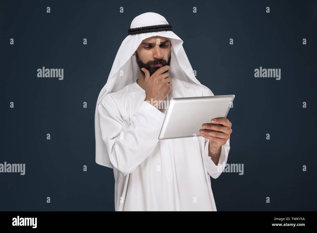 Half-length portrait of arabian saudi businessman on dark blue studio ...